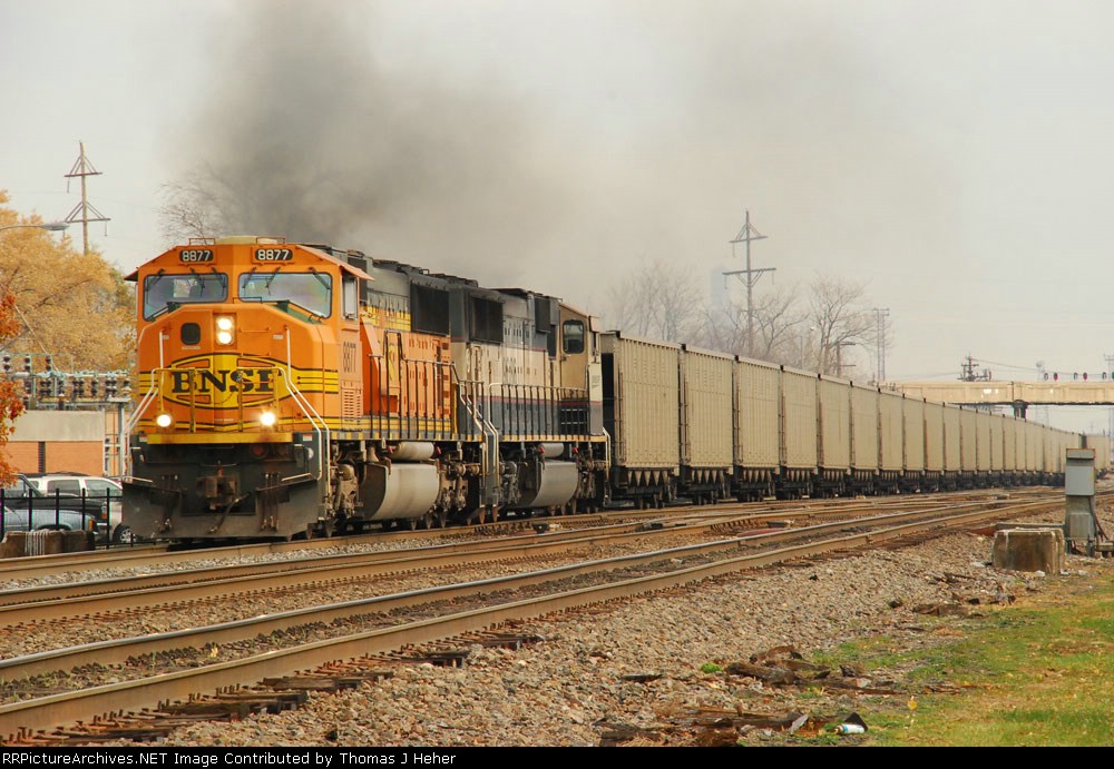 BNSF 8877 heads west with empty CEFX hoppers for PRB.